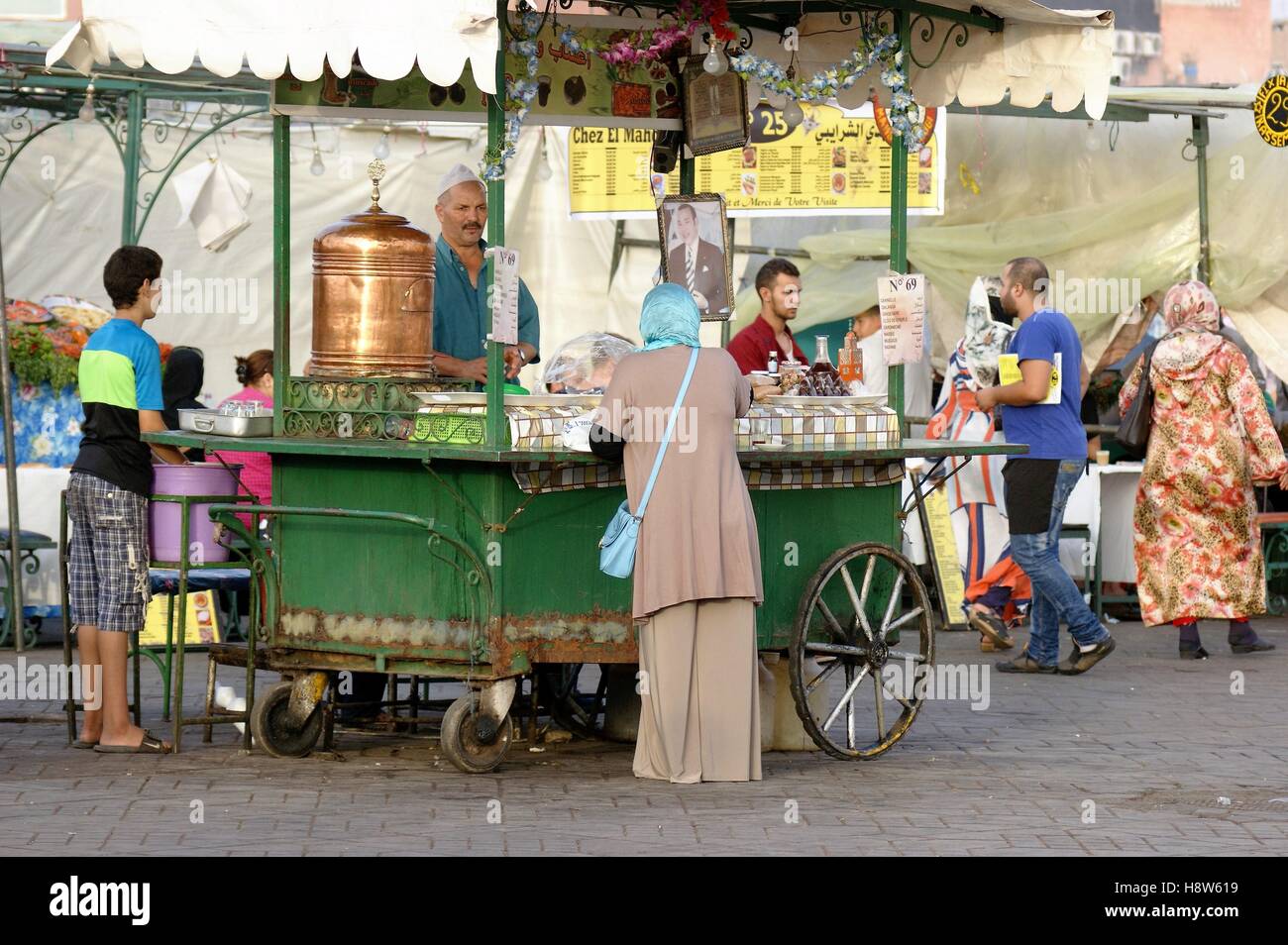 Bustling women and men around a mobile drink cart in the old town of ...