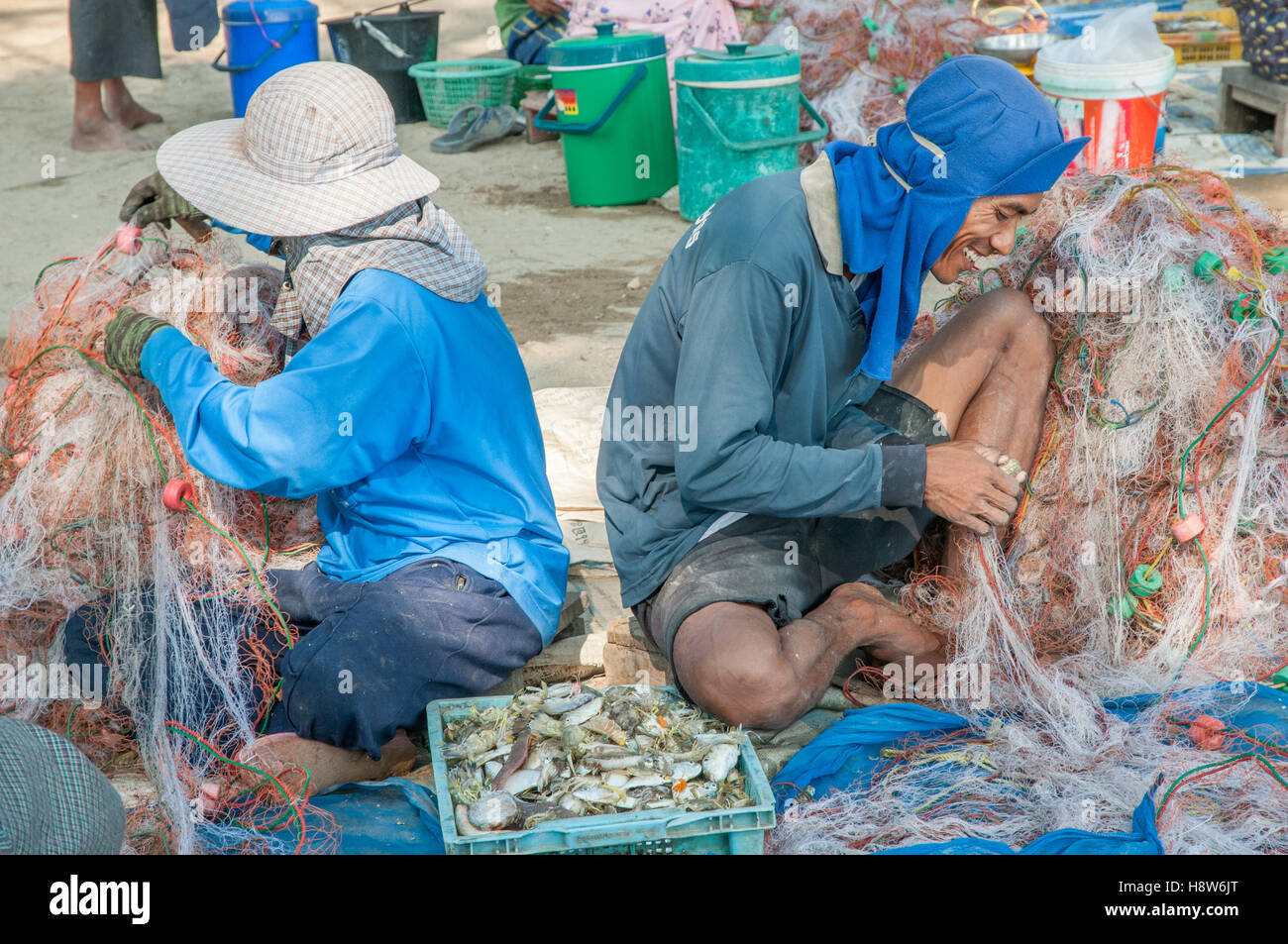 Thai people collect catch of sea food from fishing net in a village ...