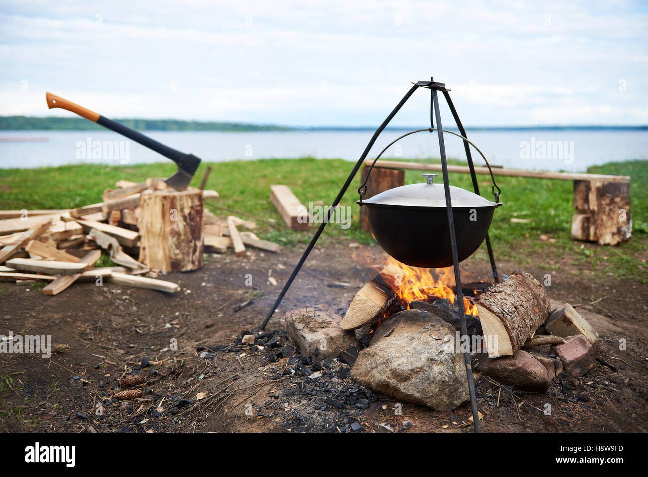 Hiking landscape with bonfire, pot and an ax Stock Photo - Alamy