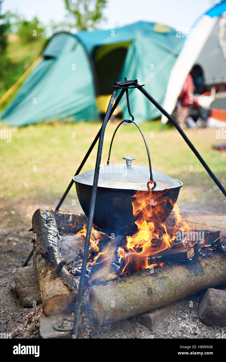 Hiking landscape with bonfire, pot and tent Stock Photo - Alamy