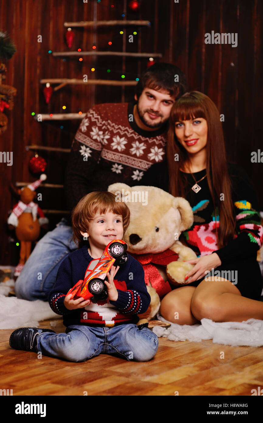 young family sitting under the Christmas tree Stock Photo - Alamy
