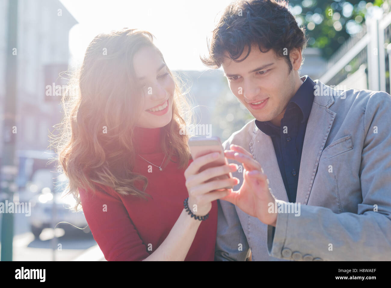 Young beautiful couple in love using smart phone together outdoor in ...