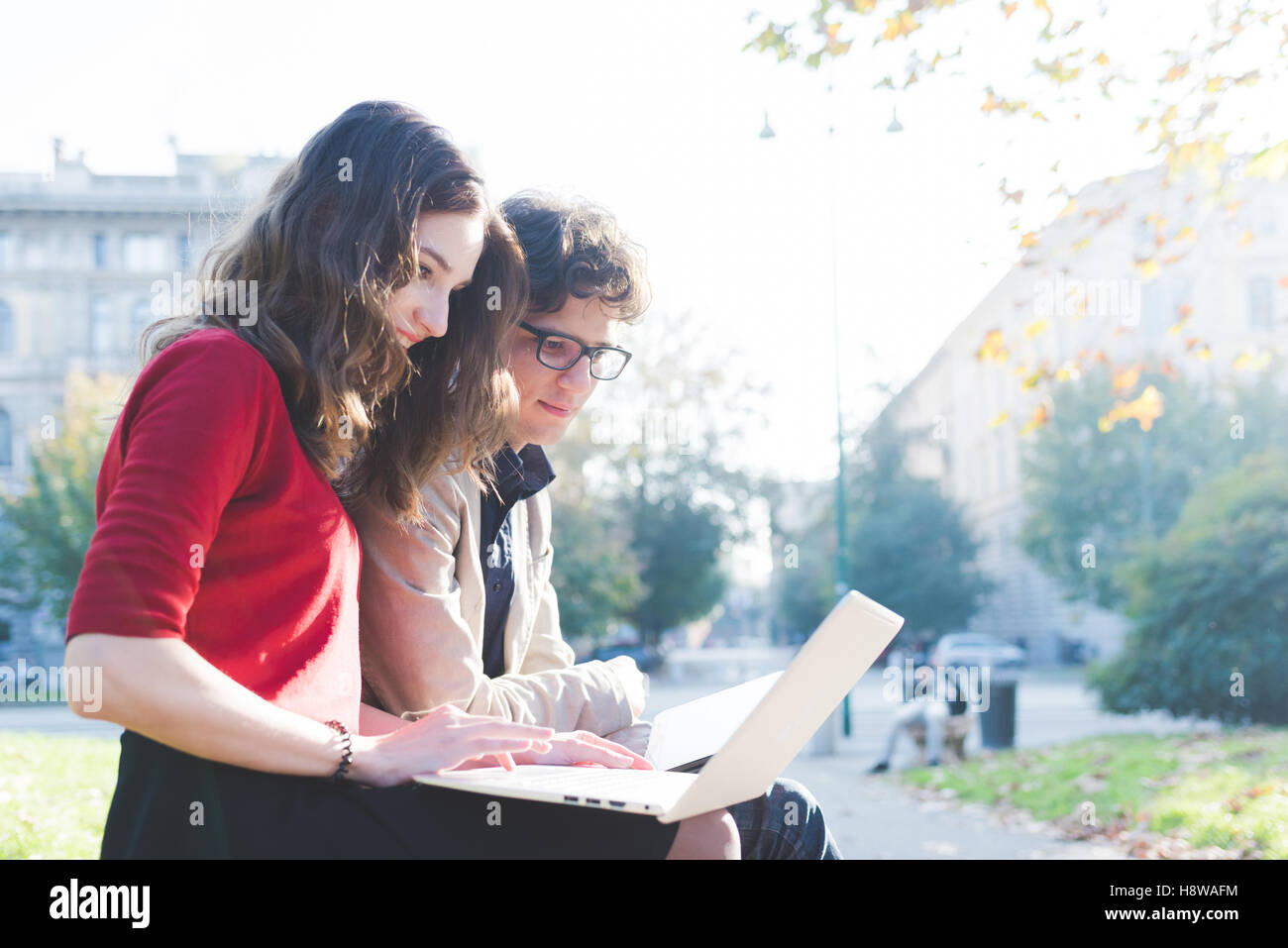 Young beautiful couple in love outdoor in the city using computer ...