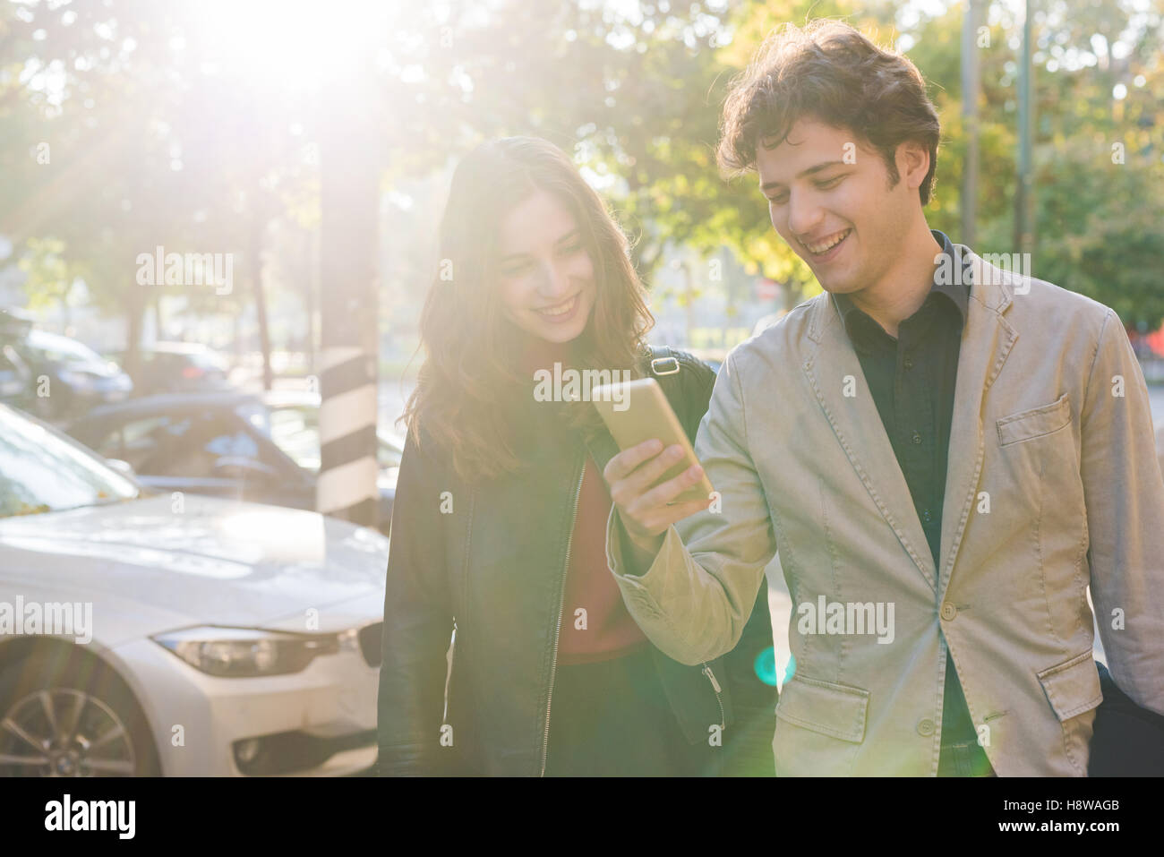Young beautiful couple in love using smart phone together outdoor in ...
