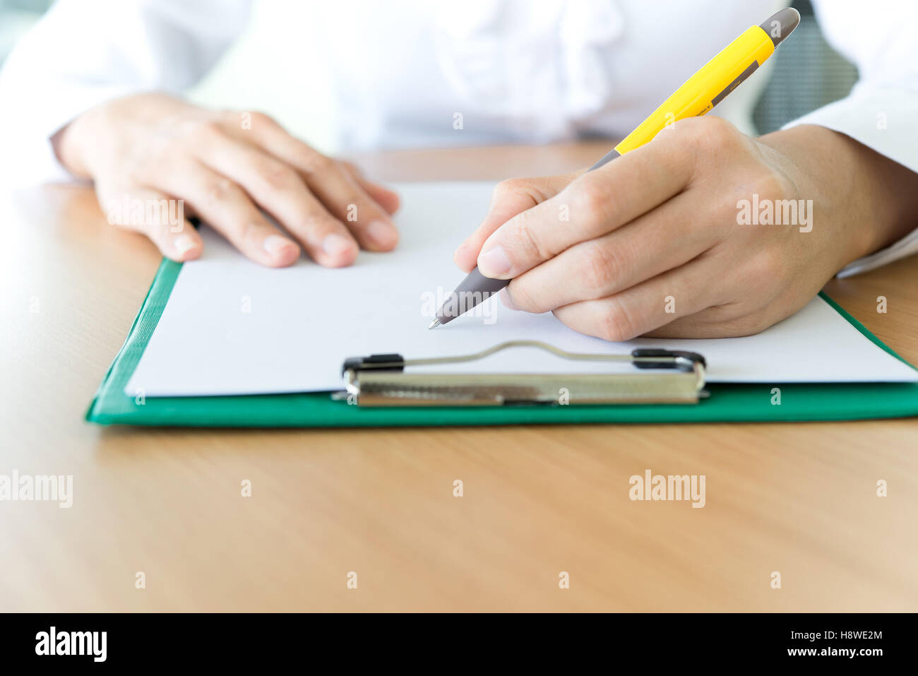 Close-up of pen in female hands. Woman writing something on table ...
