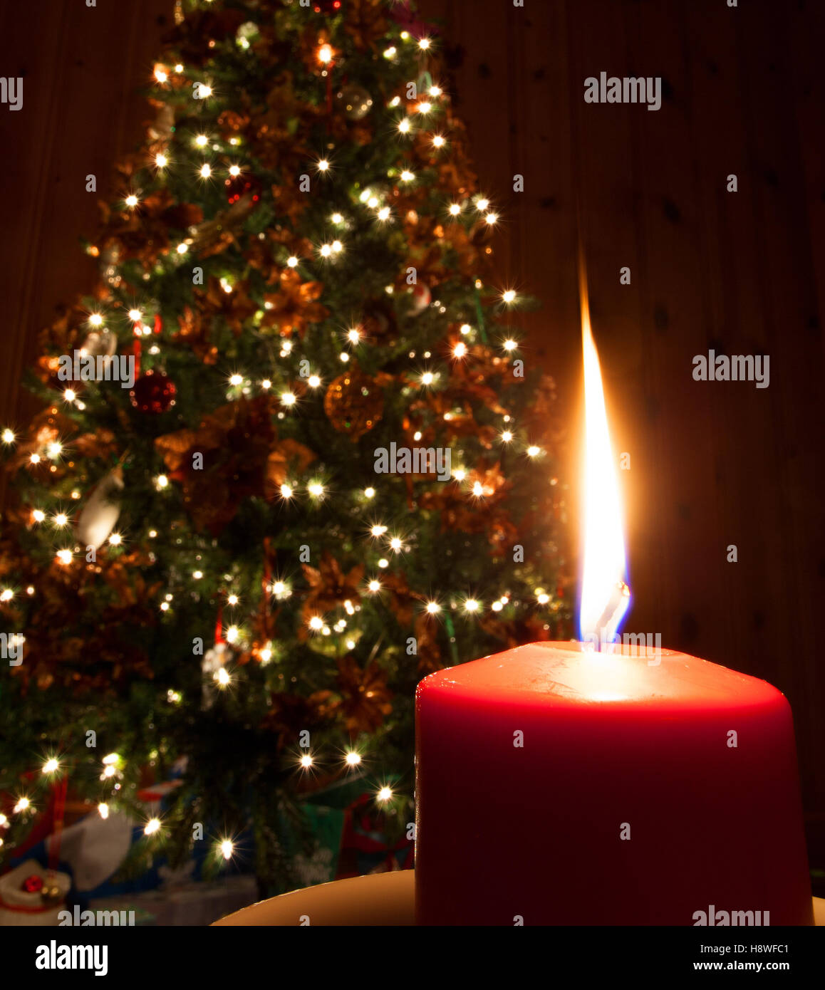 Flame coming from a red candle in front of a Christmas tree Stock Photo ...