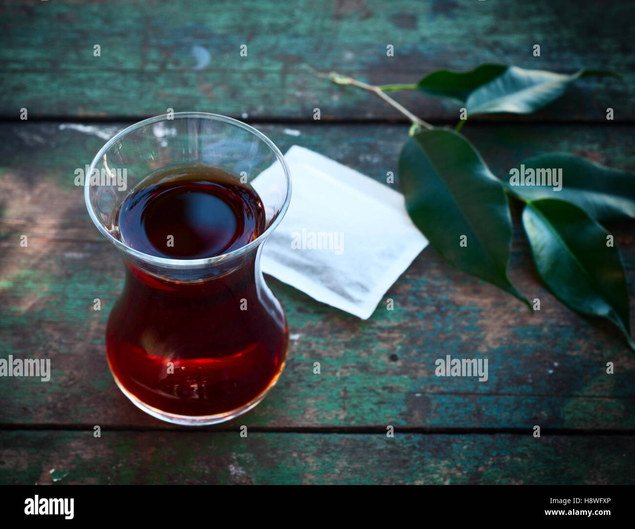 Turkish glass cup with black tea, near branch with leaves Stock Photo ...