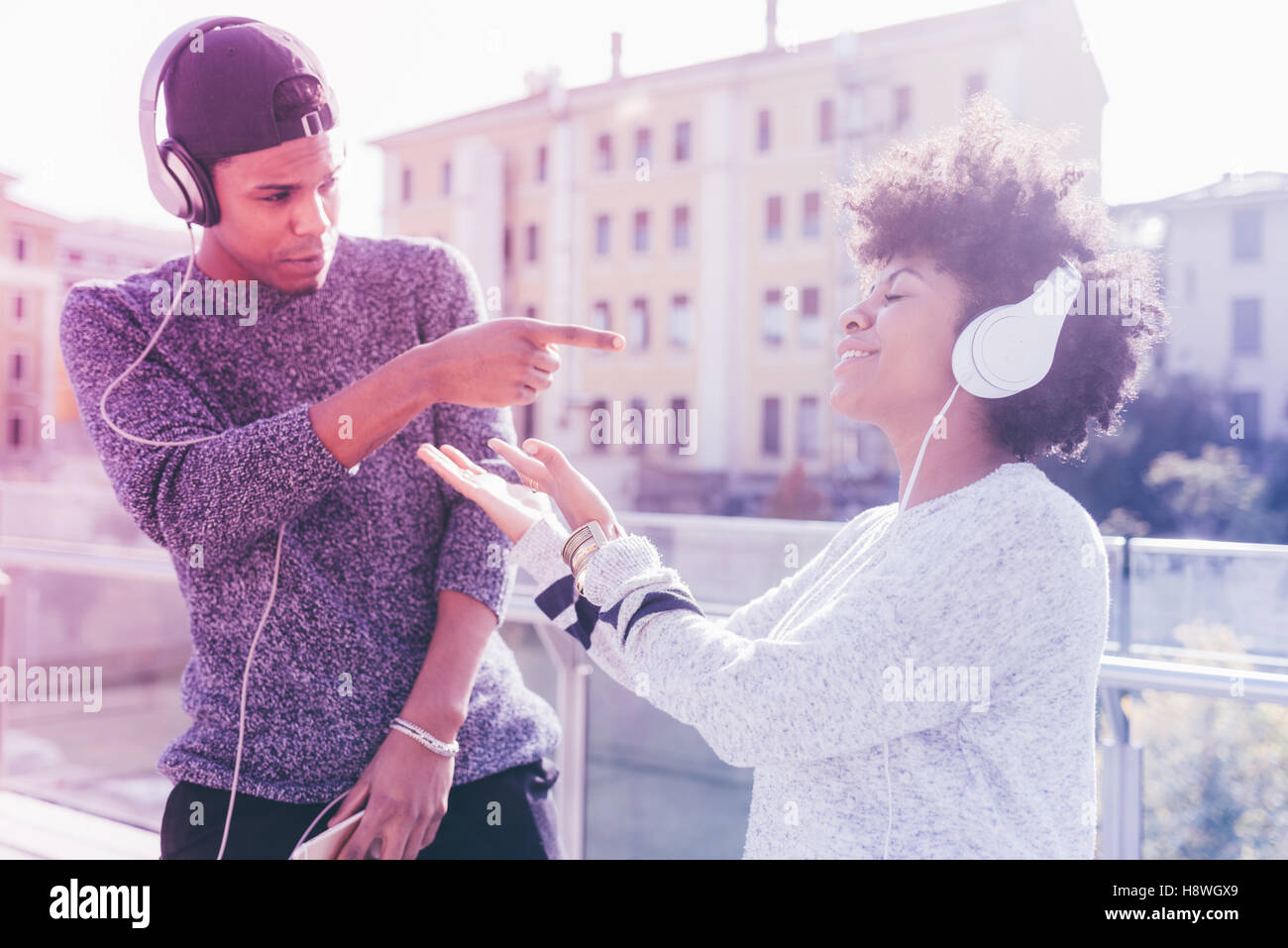 Young multiethnic couple outdoor in the city listening music with head ...