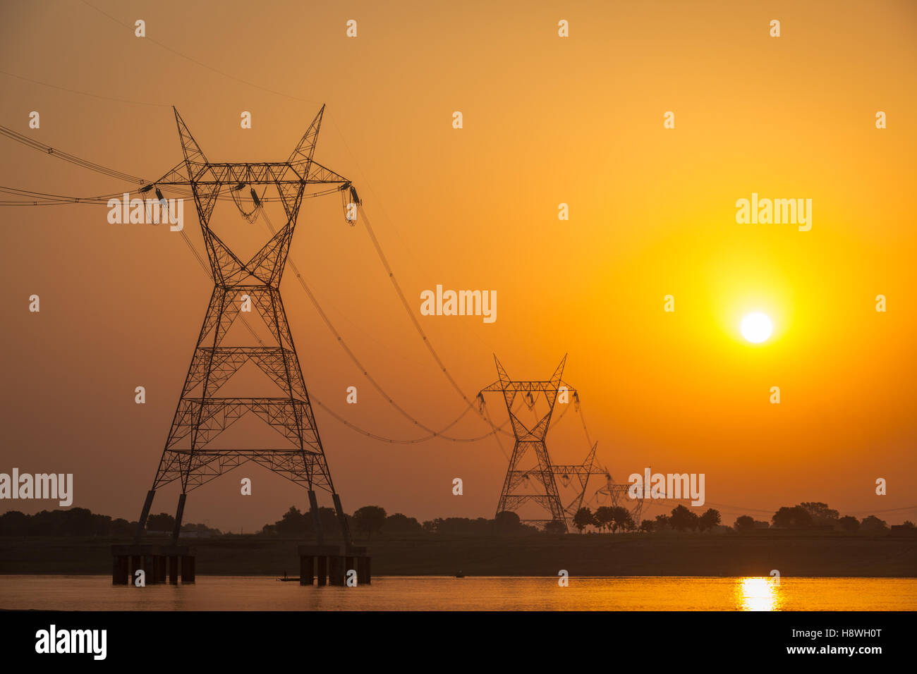 Electricity pylons pictured against a rising sun over the River Ganges ...