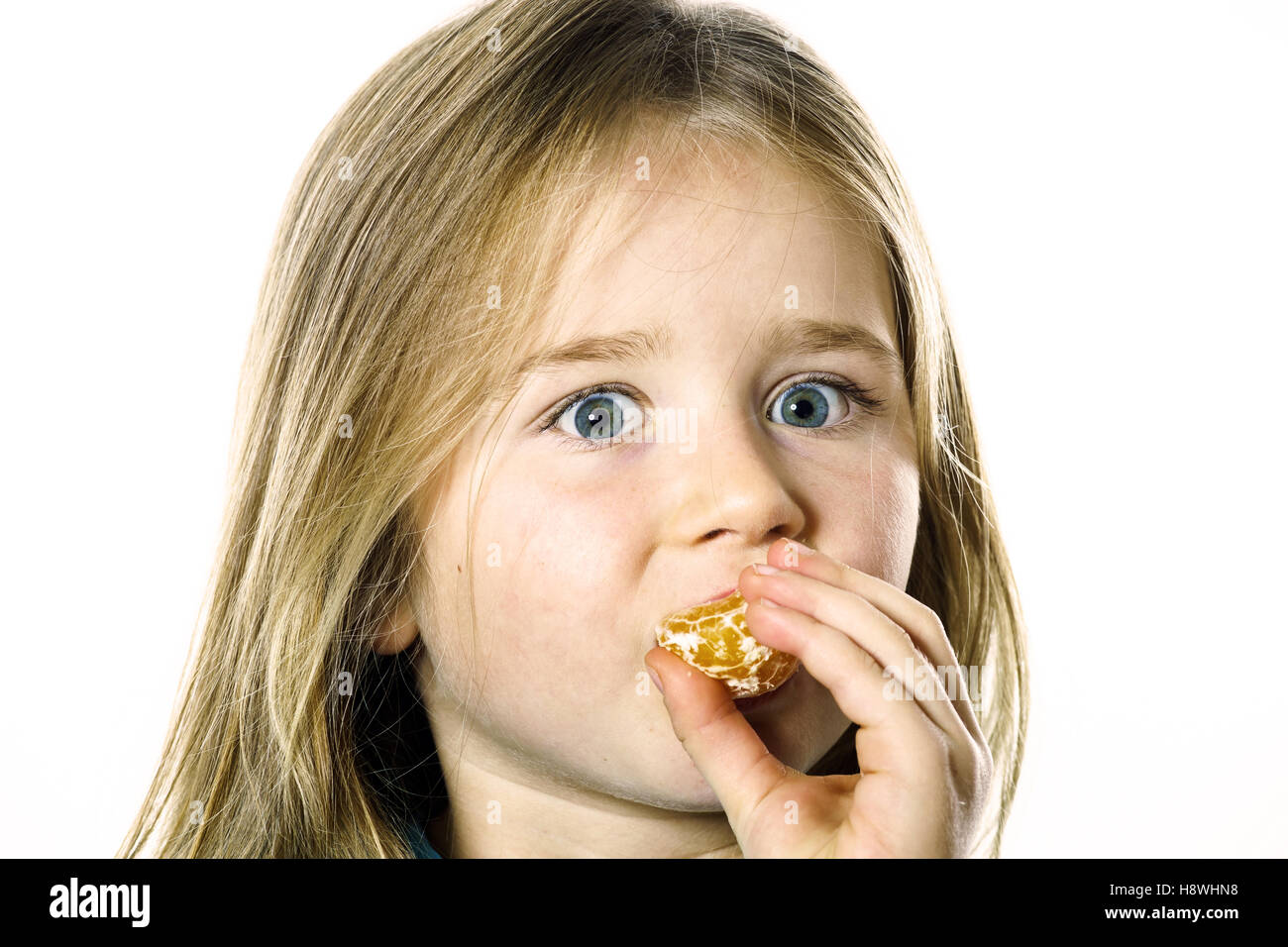 Little girl eating mandarin, closeup view, isolated on white background ...