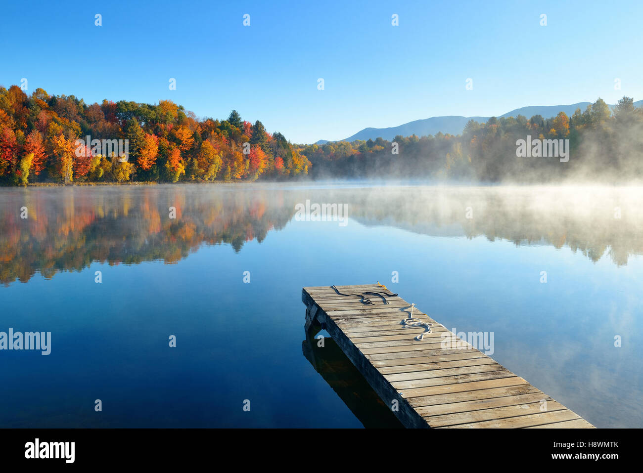 Autumn foliage and fog lake in morning with boat dock Stock Photo - Alamy