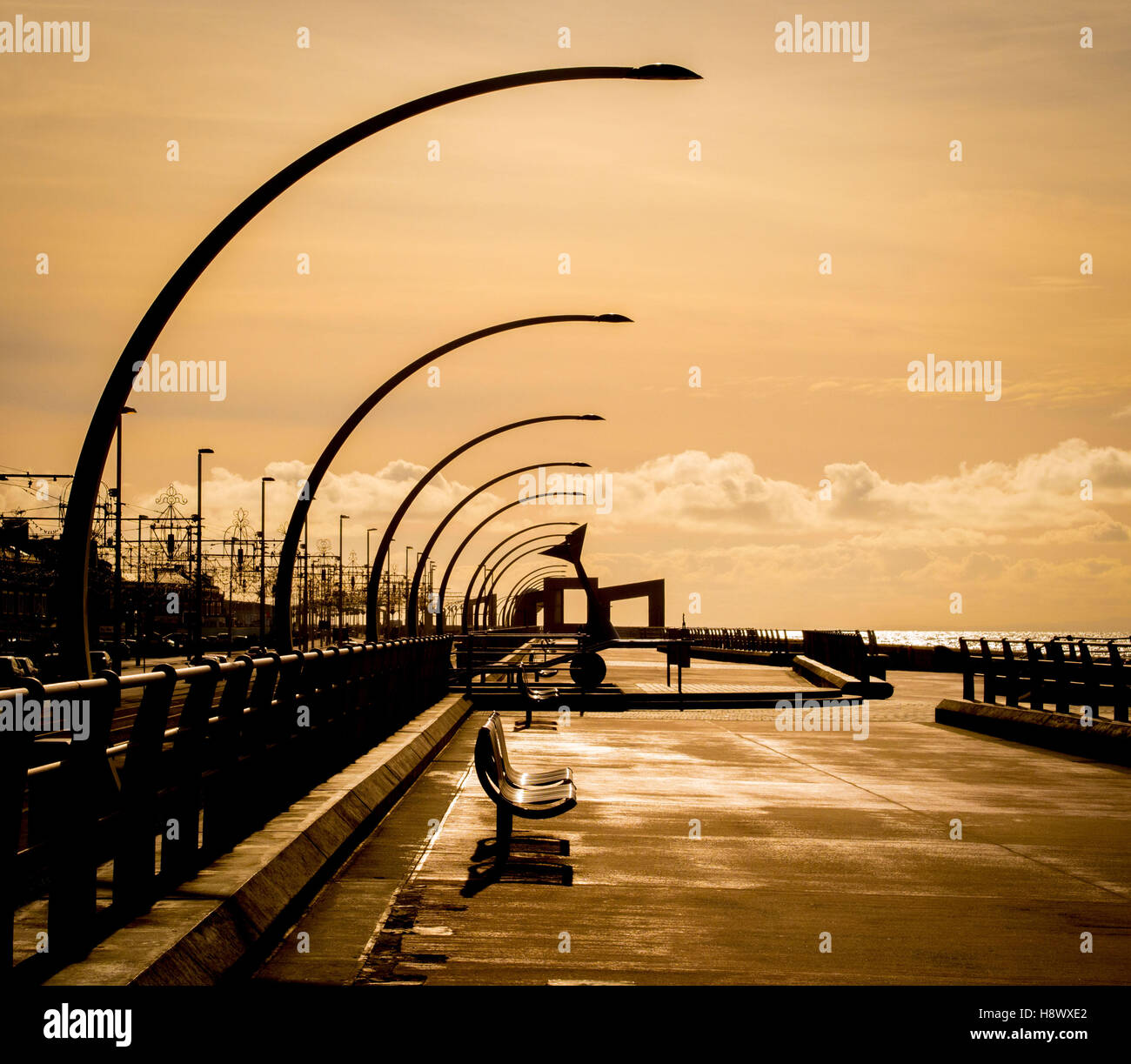 Seafront promenade with modern arched lights and golden sunlight ...