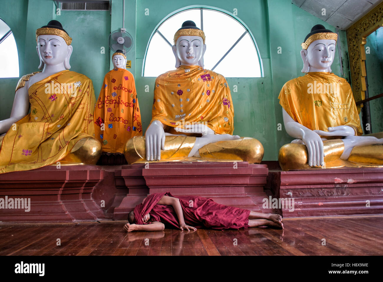 Burmese monk sleeping in front of Buddha statues Stock Photo - Alamy