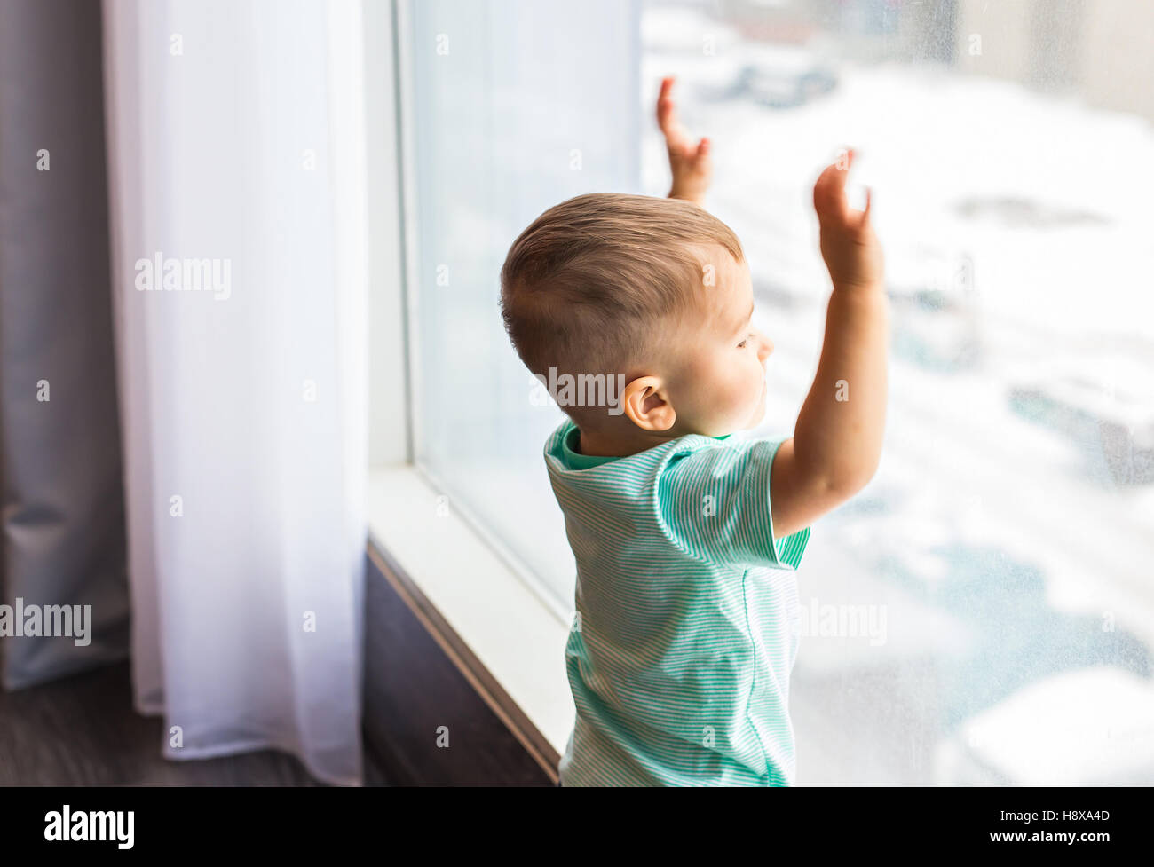 Little boy looking out the window Stock Photo - Alamy