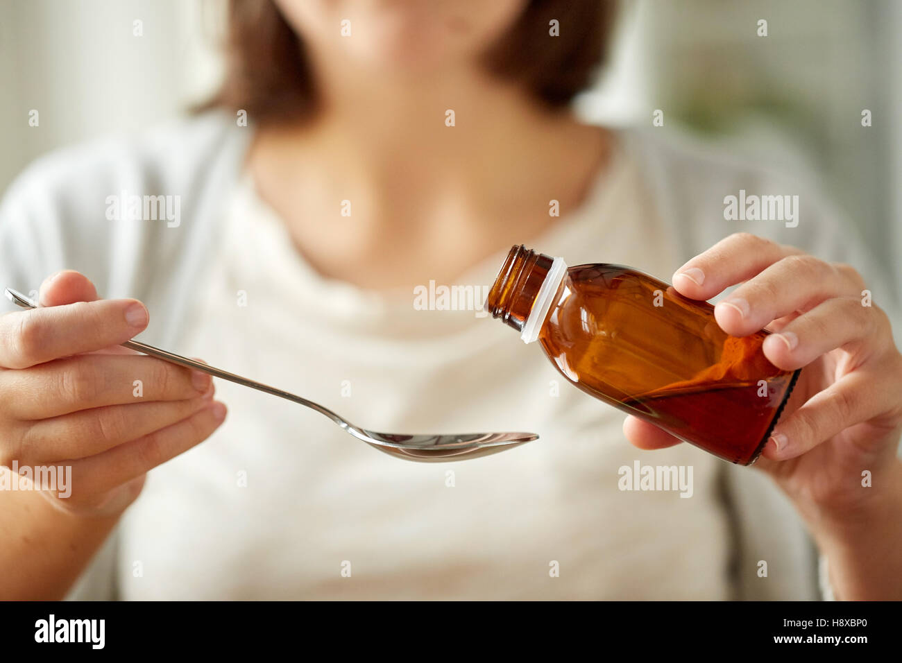 woman pouring medication from bottle to spoon Stock Photo - Alamy