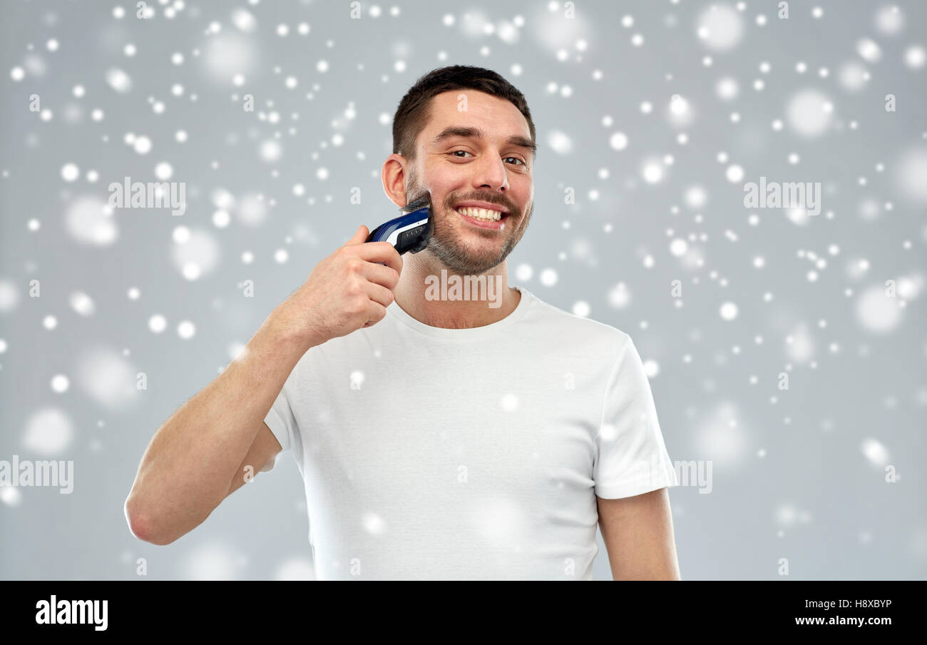 smiling man shaving beard with trimmer over snow Stock Photo - Alamy