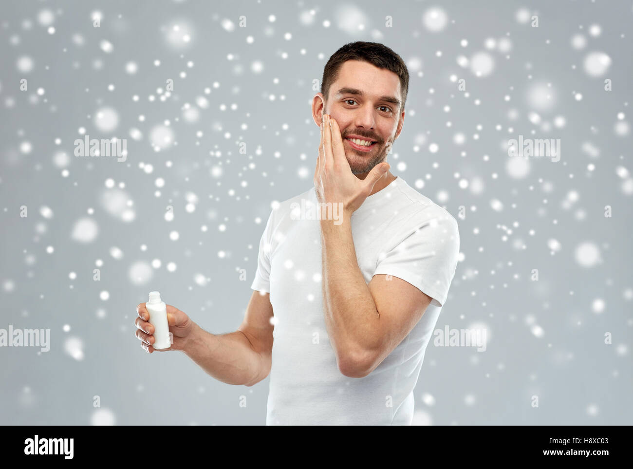 happy young man applying cream or lotion to face Stock Photo - Alamy