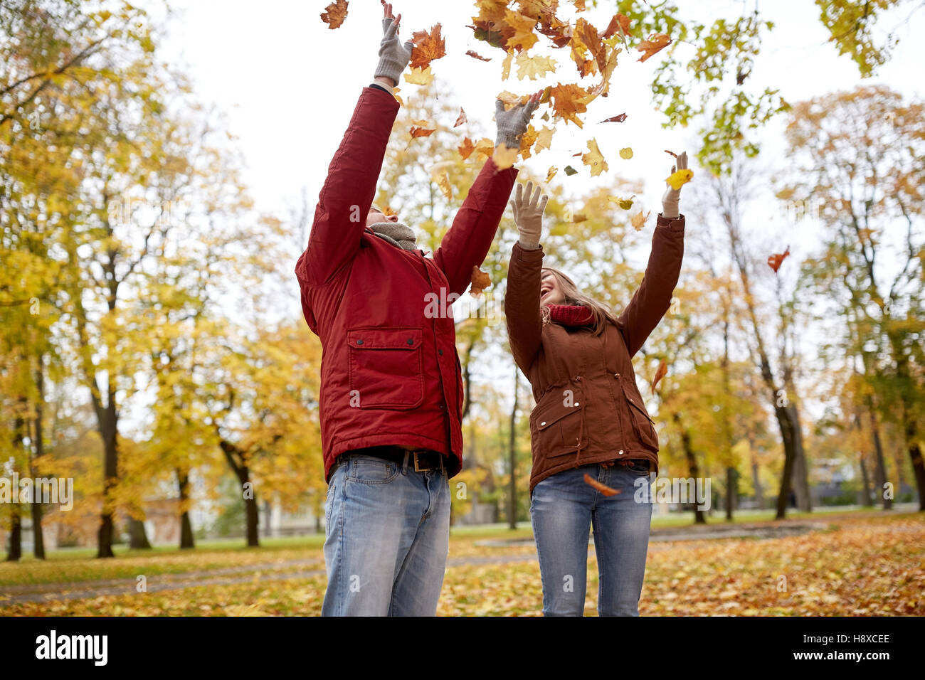 happy young couple throwing autumn leaves in park Stock Photo - Alamy