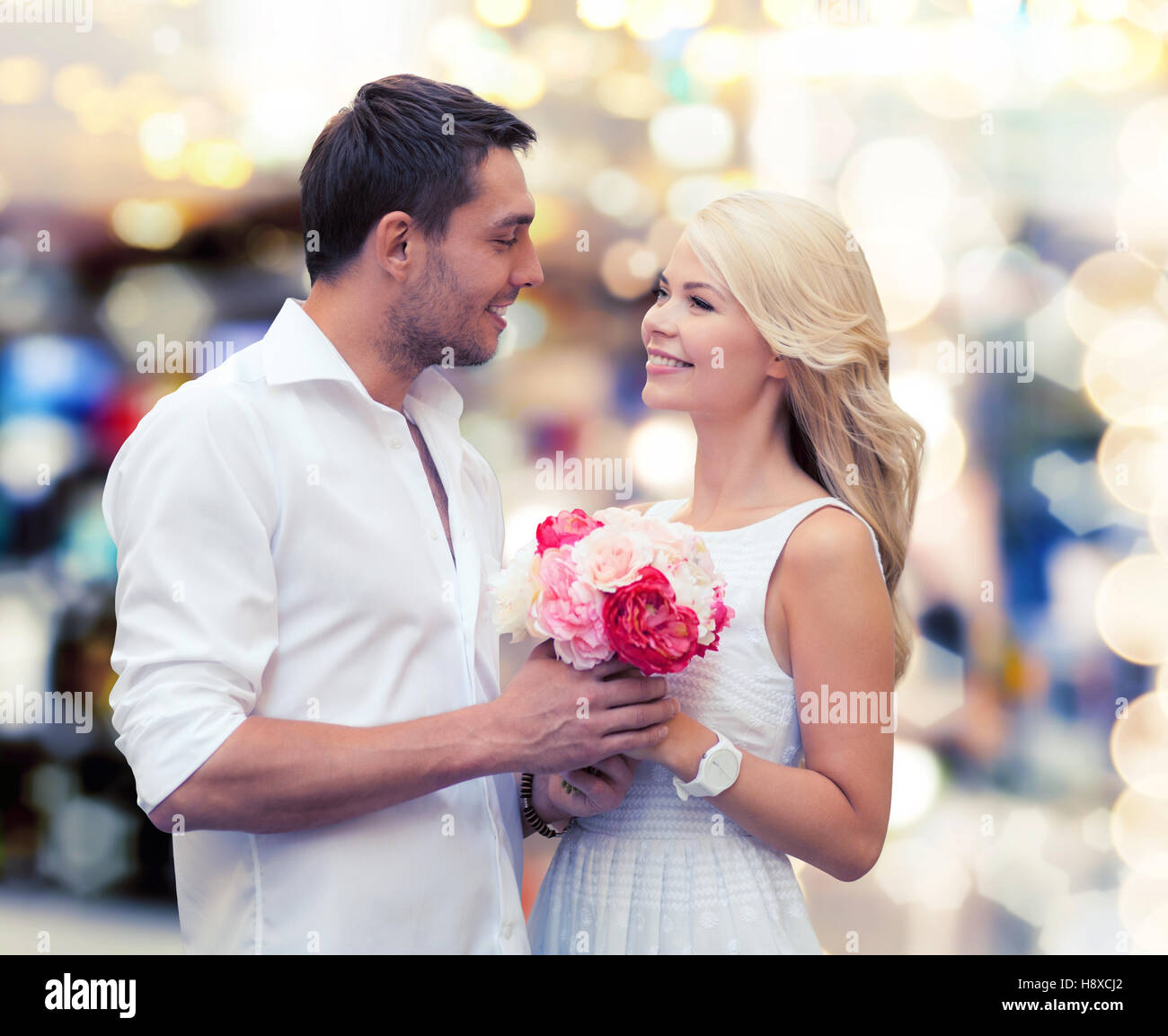 happy couple with flowers over lights background Stock Photo - Alamy