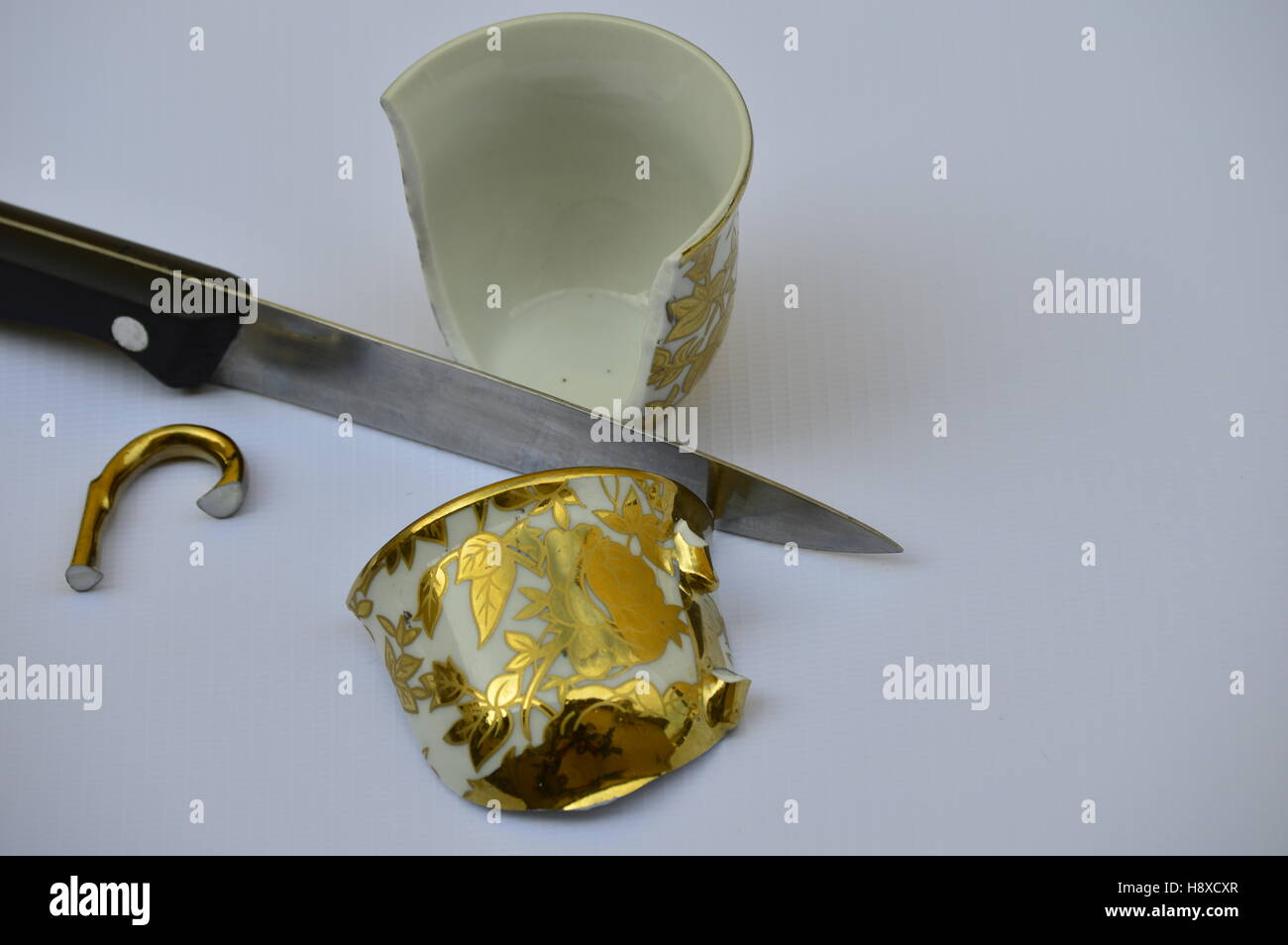 Broken cup of tea, and knife Stock Photo - Alamy