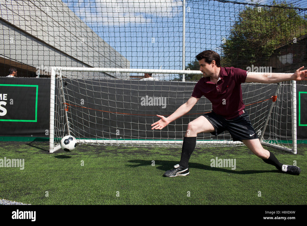 A goalkeeper saves a penalty during a match at an all weather football ...