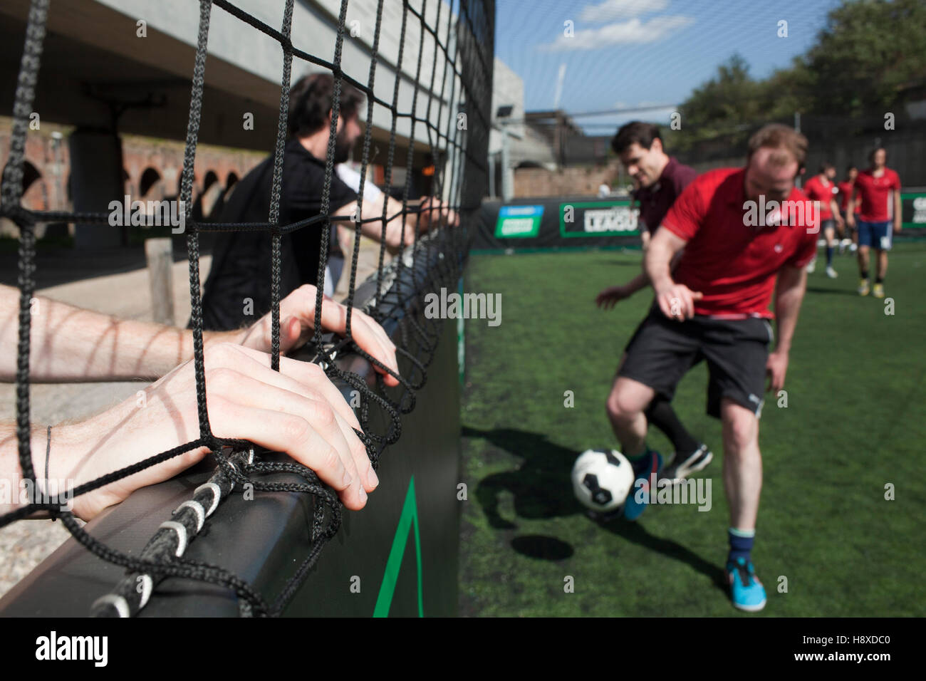 Spectators watch a football match on an all weather pitch in east ...