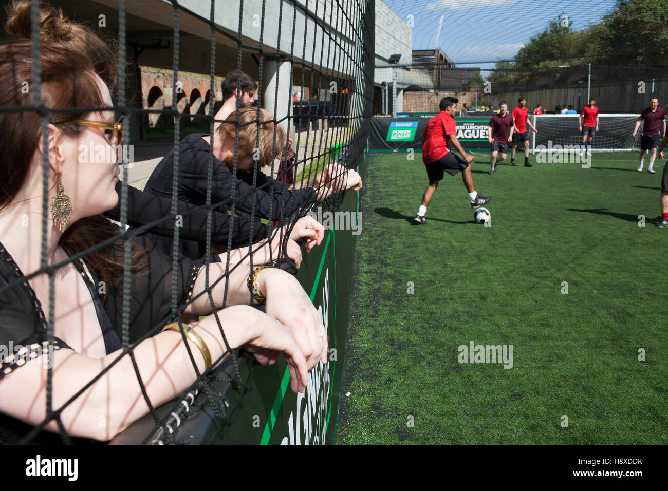 Spectators watch a football match on an all weather pitch in east ...