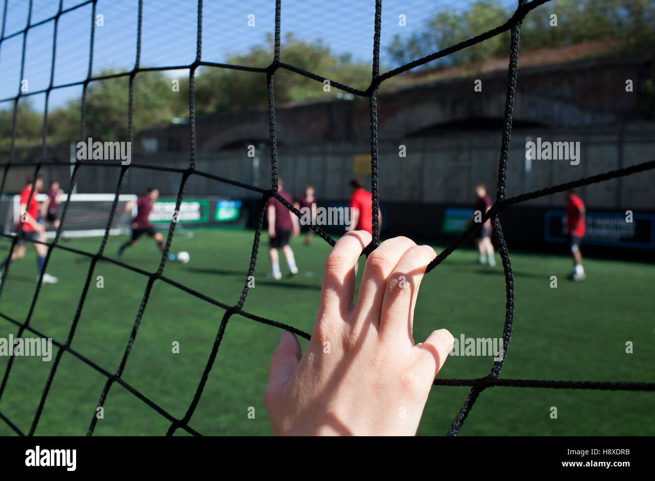 A hand on a safety net around an all weather football pitch Stock Photo ...