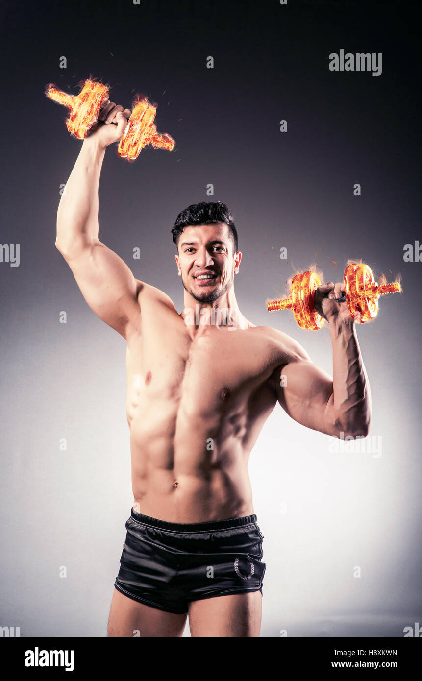 Muscular ripped bodybuilder with burning dumbbells Stock Photo - Alamy