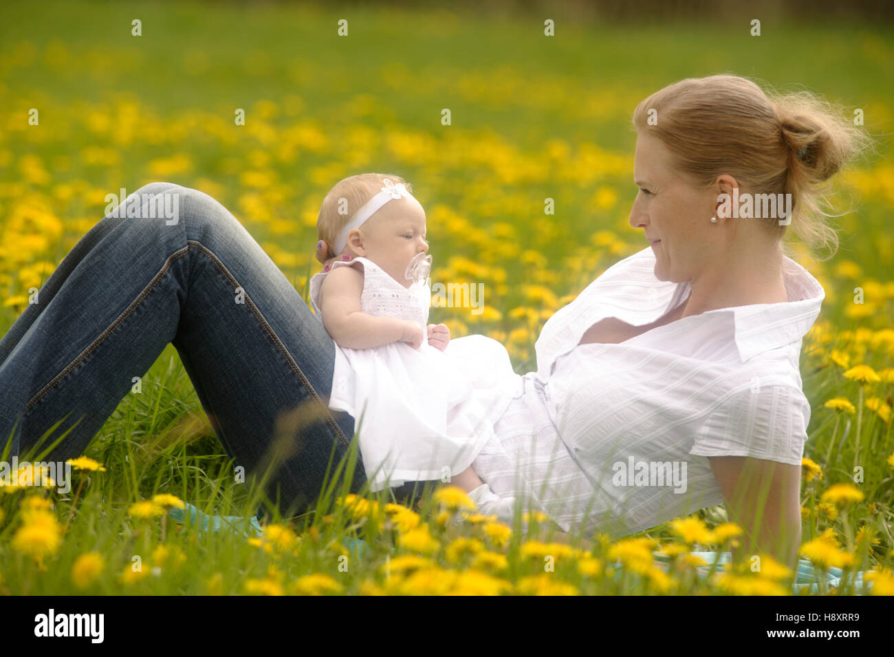 Mother with baby, girl, in a spring meadow Stock Photo - Alamy