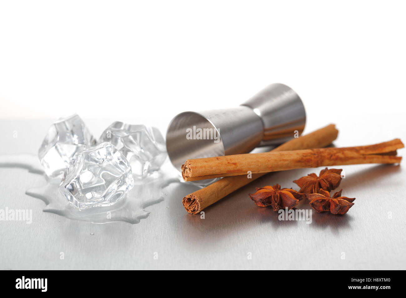 Jigger, melting ice cubes and spices on a stainless steel surface Stock ...