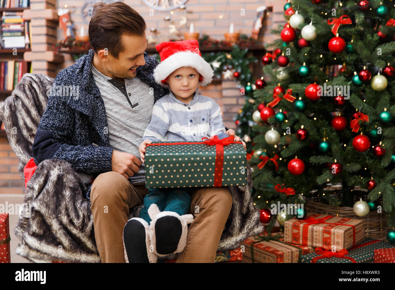 Dad and son in easy chair at Christmas tree Stock Photo - Alamy