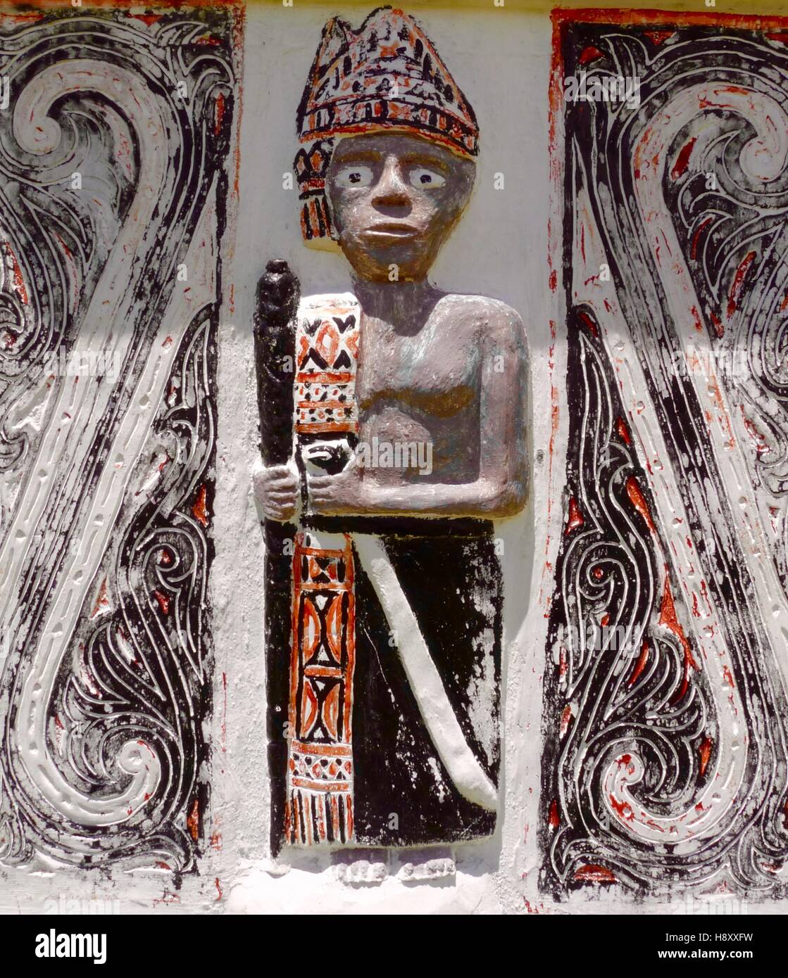 Carving of figure of Batak hunter with traditional colours and design ...