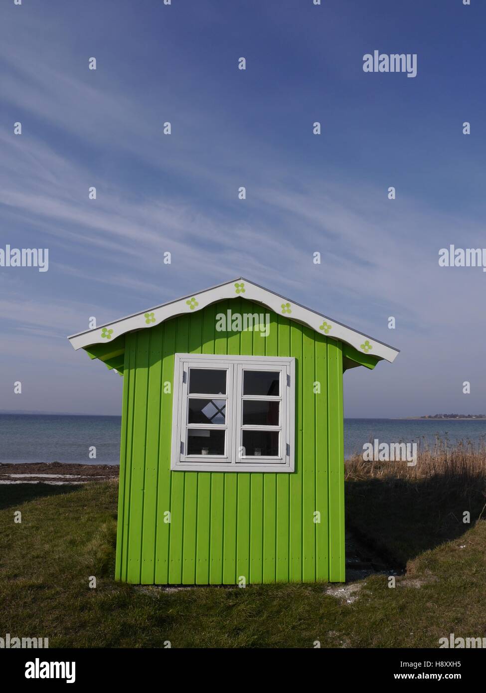 A cute lime-green beach hut with white roof and window frame against a ...