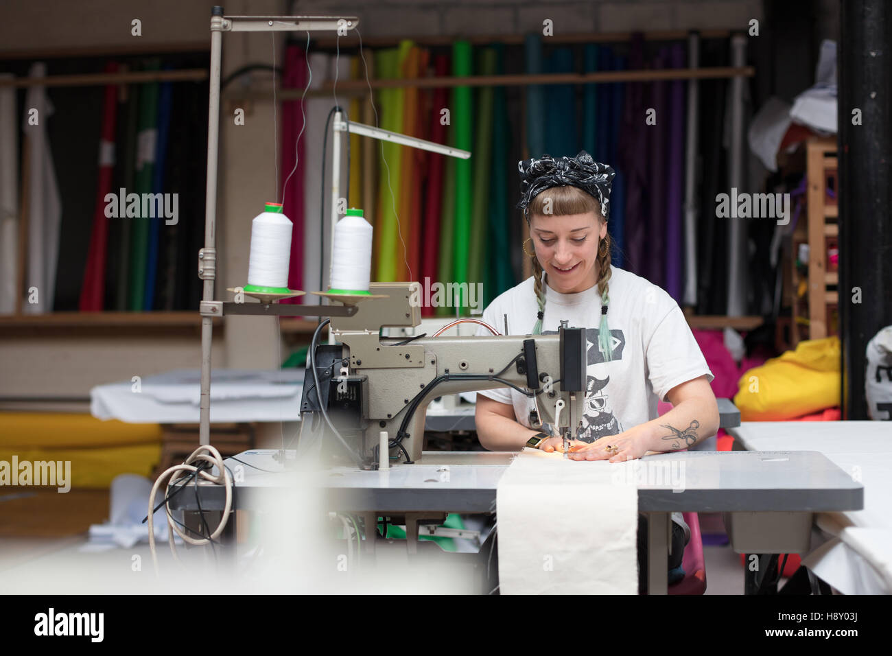 Young tattooed seamstress sewing in a factory environment Stock Photo ...