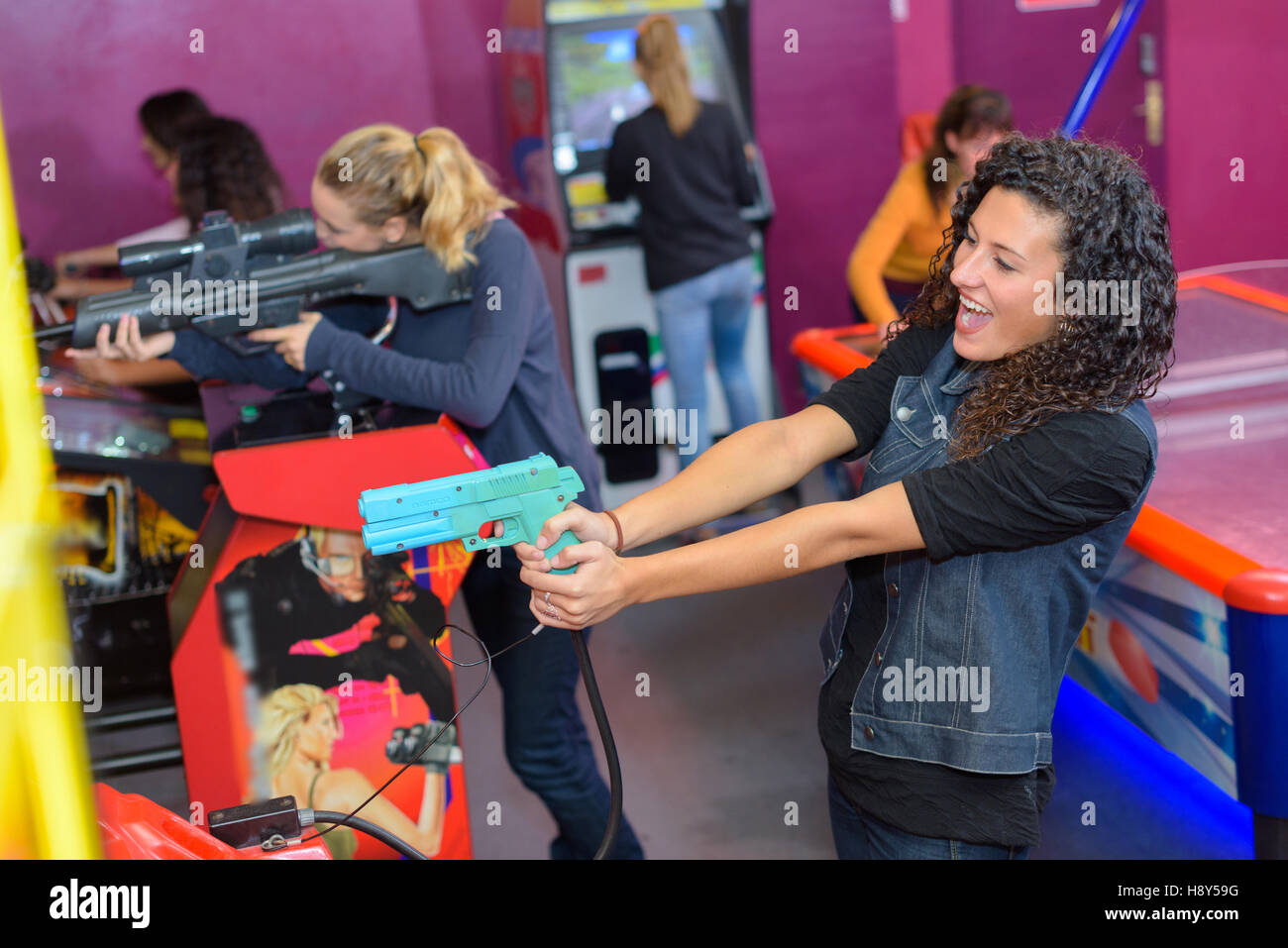 Women firing guns playing arcade game Stock Photo - Alamy