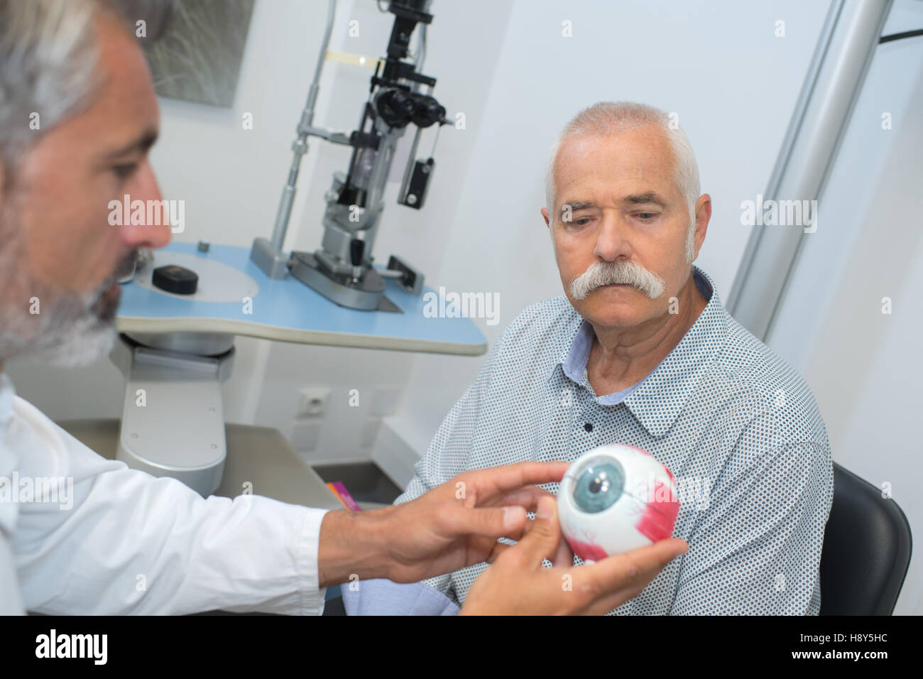ophthalmologist shows an old patient his view problem Stock Photo - Alamy