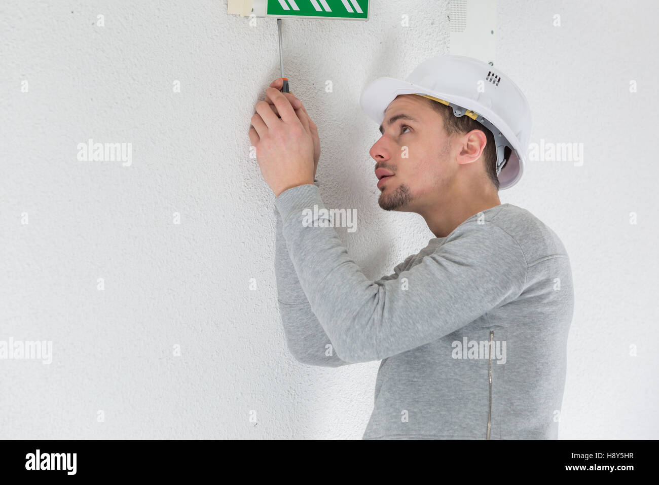 a male electrician fixing electric sign on the ceiling Stock Photo - Alamy