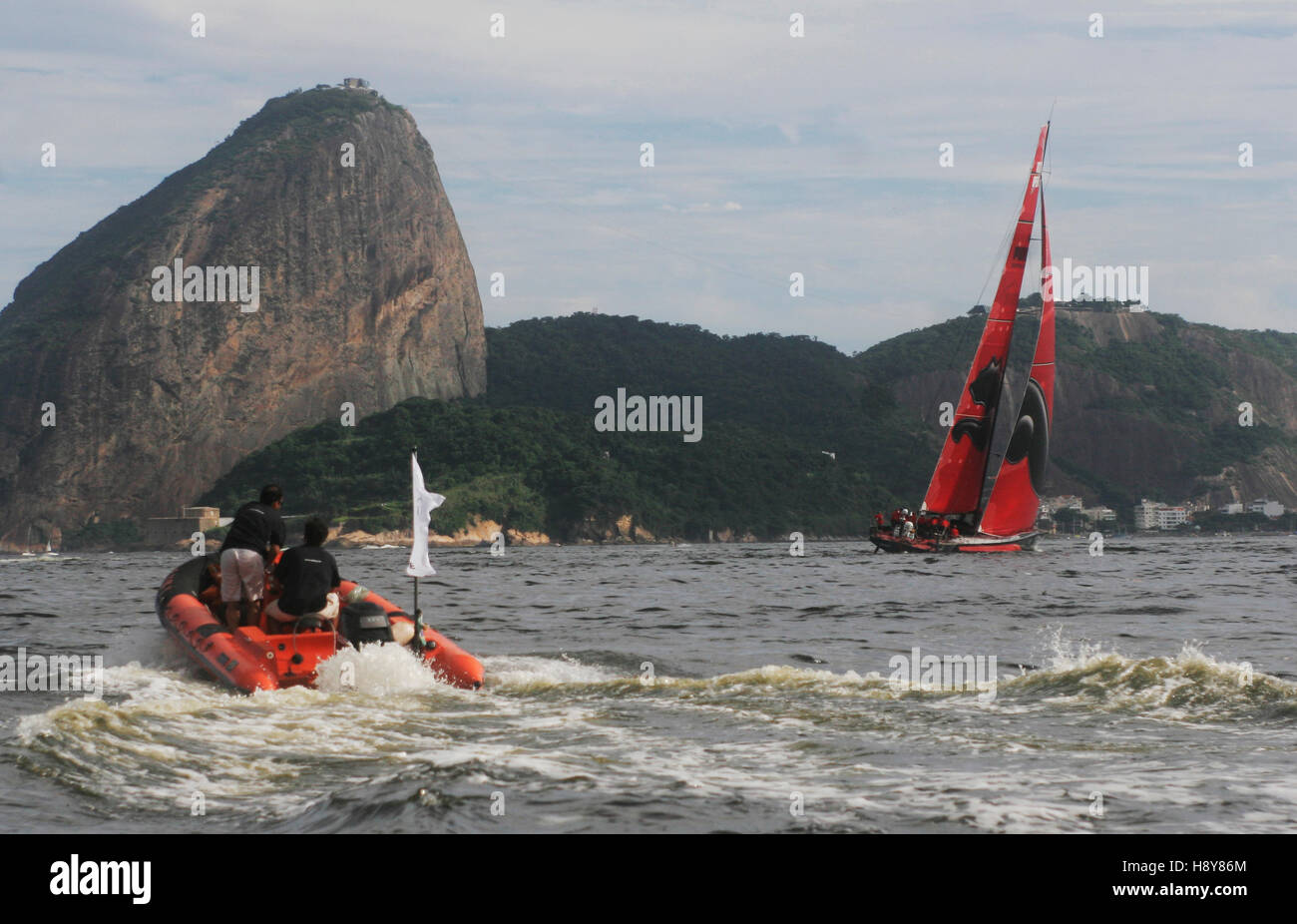Support boat chasing sailboat during race Stock Photo - Alamy