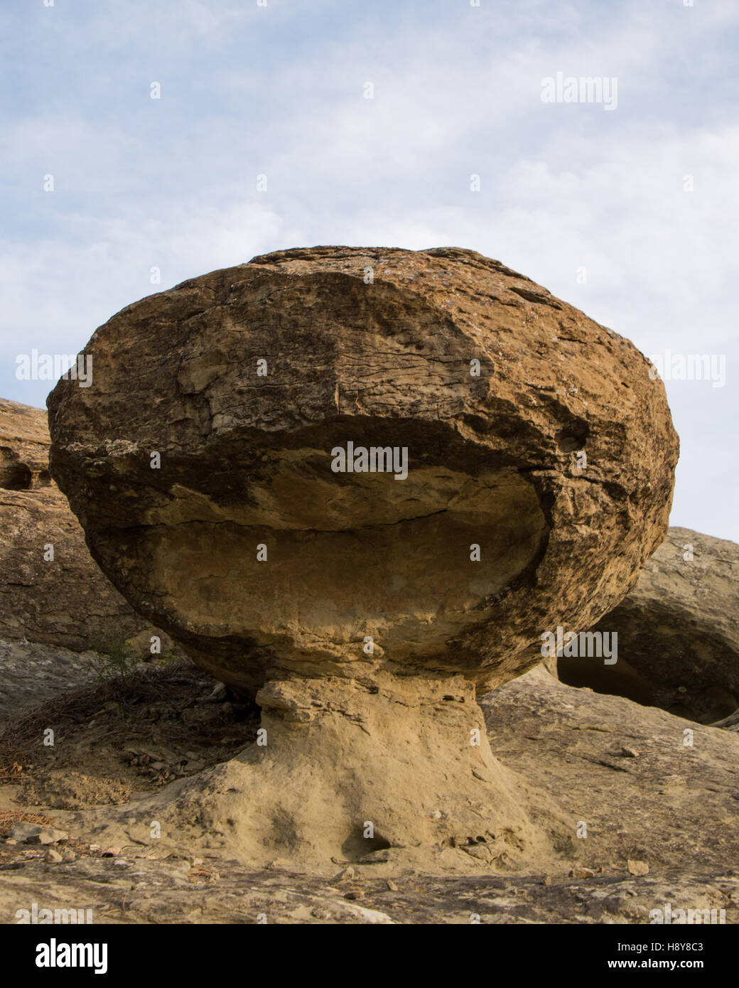 A large spherical sandstone formation on a stone pedestal with a mouth ...