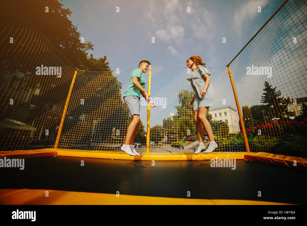 Couple jumping on trampoline in the park Stock Photo - Alamy