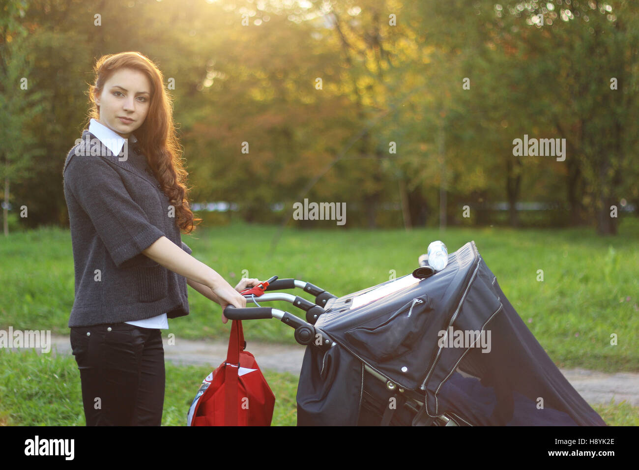 Mom with stroller walks in autumn park alley Stock Photo - Alamy