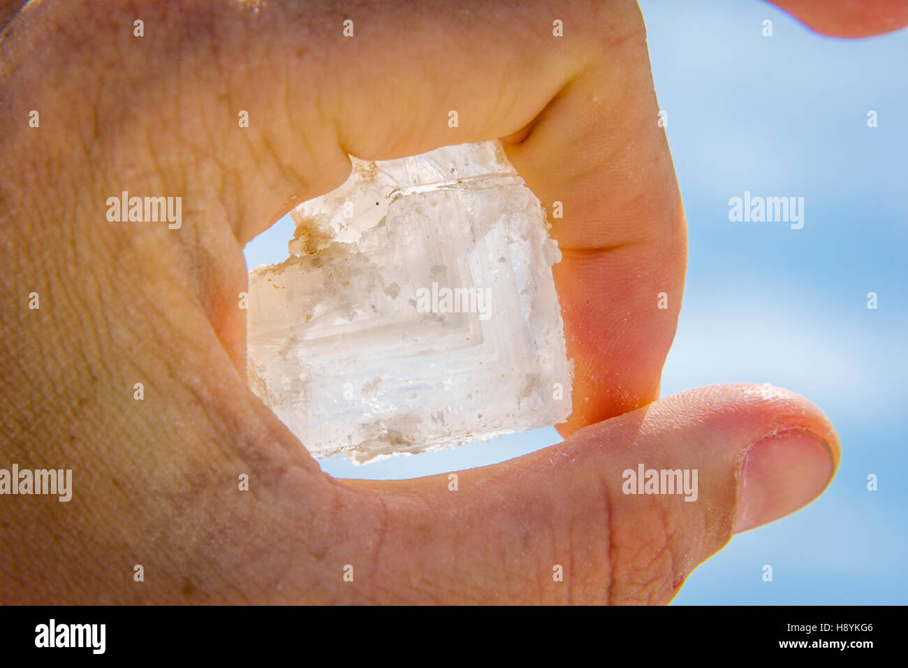 Holding big salt crystal in hand against blue sky Stock Photo - Alamy