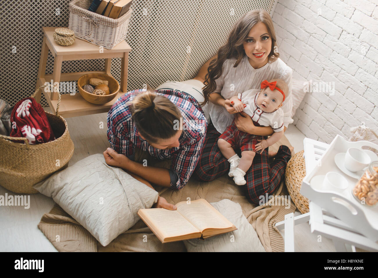 Young family reading story indoors Stock Photo - Alamy