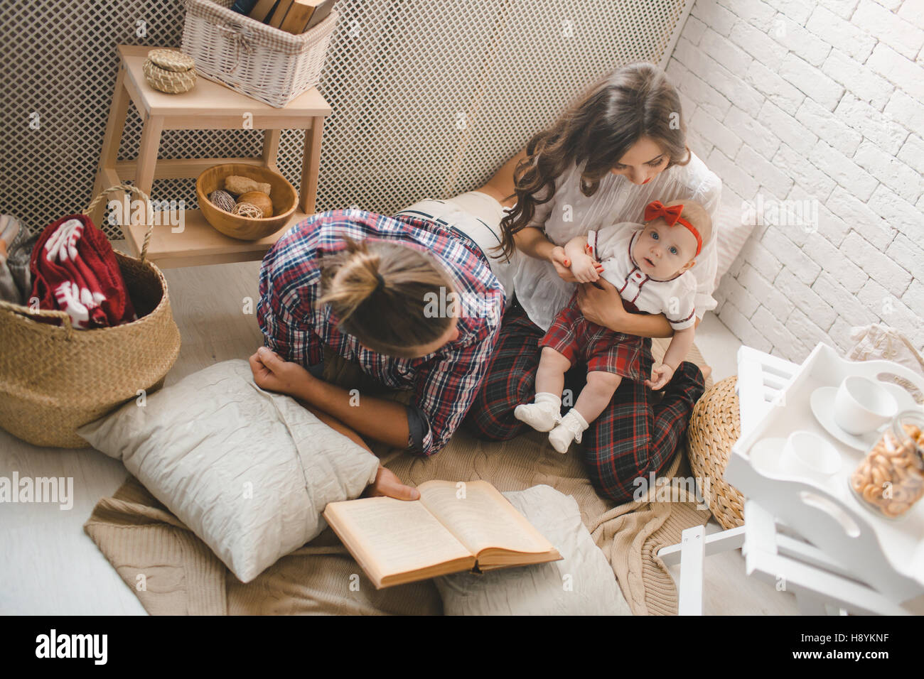 Young family reading story indoors Stock Photo - Alamy