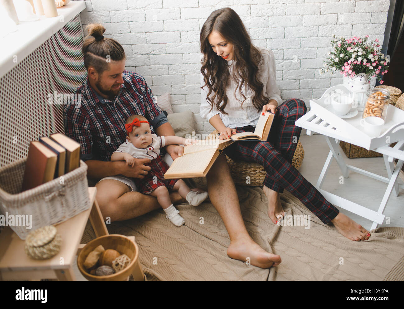 Young family reading story indoors Stock Photo - Alamy