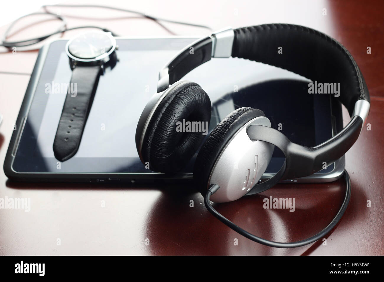 Headphones on a table next to the tablet and a clock Stock Photo - Alamy
