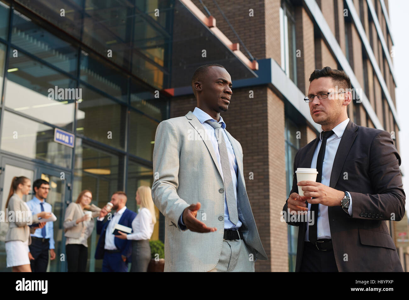 Two professionals communicating outdoors at break Stock Photo - Alamy