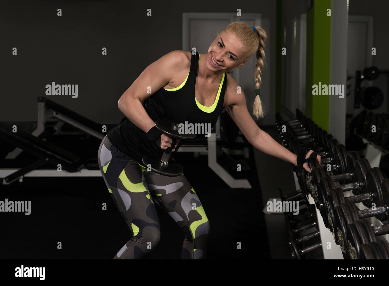 Woman Exercising Back With Dumbbells In The Gym And Flexing Muscles ...