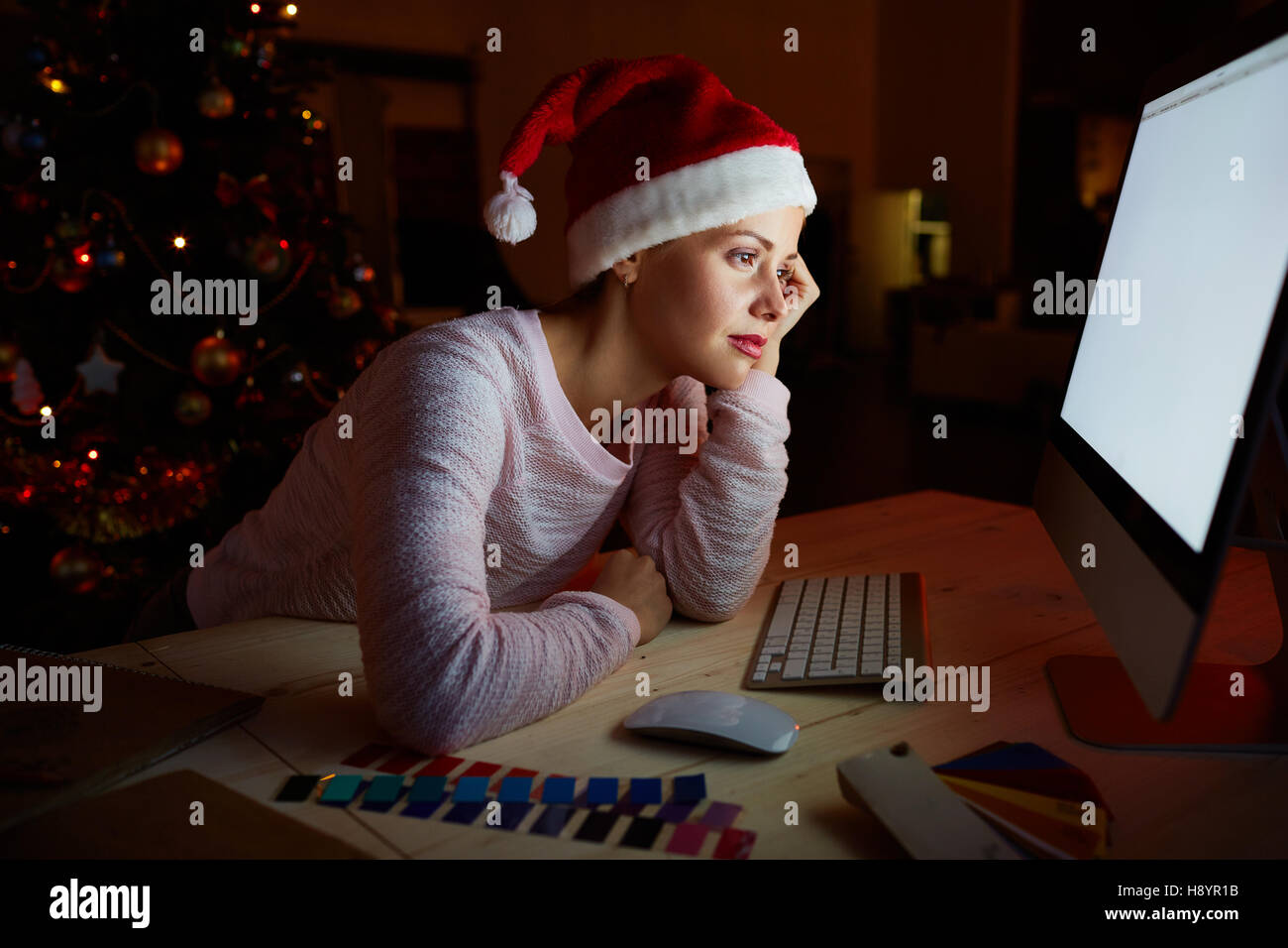 Bored young woman spending xmas night on her own in front of computer ...